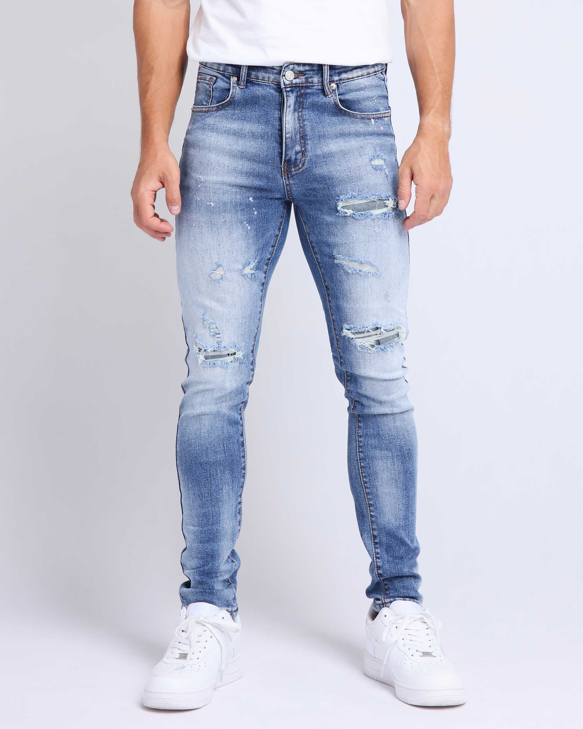 Jeans rasgados azules con pintura en aerosol con lavado irregular para ...